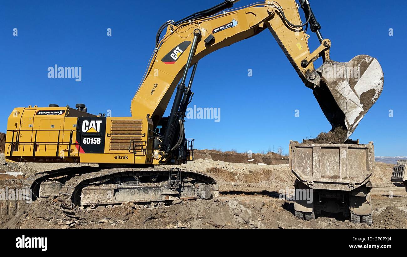 Excavator is loading continuously the trucks, working at a huge mining ...