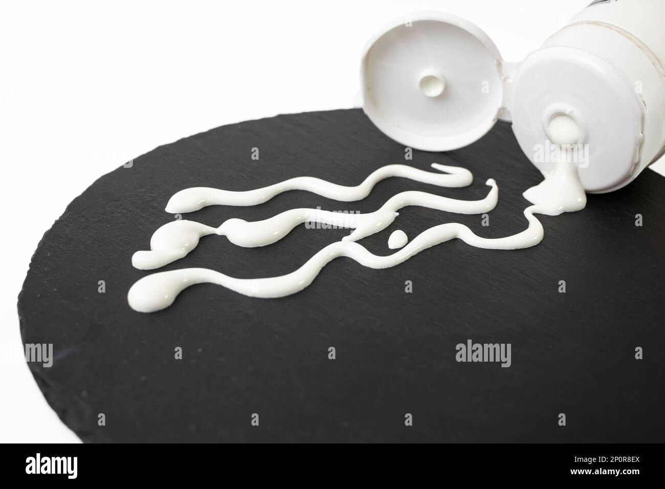 White cream waves on black stone texture, from a plastic cap tube, soft ...