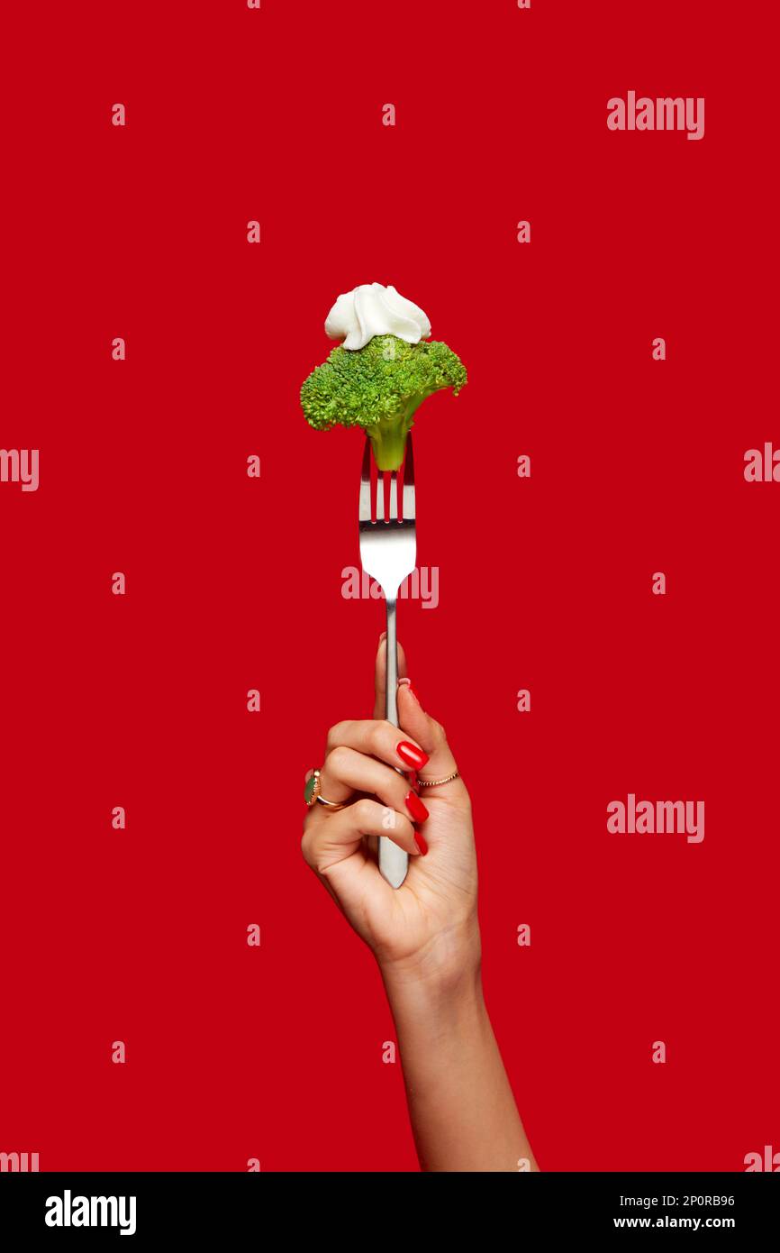 Food pop art photography. Female hand holding broccoli on fork against ...