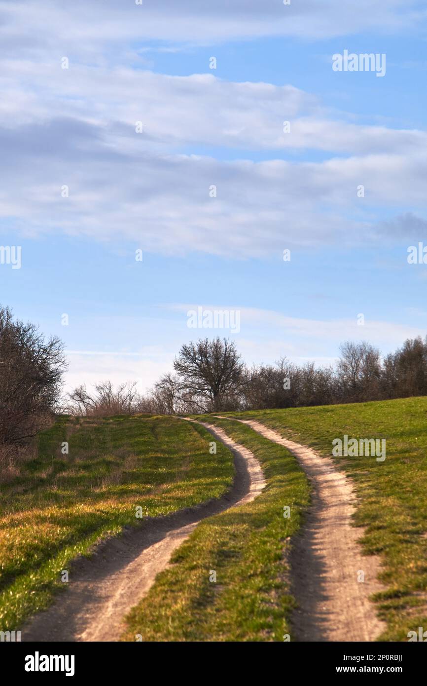 Dirt rural road winding across countryside highlands at the border of ...