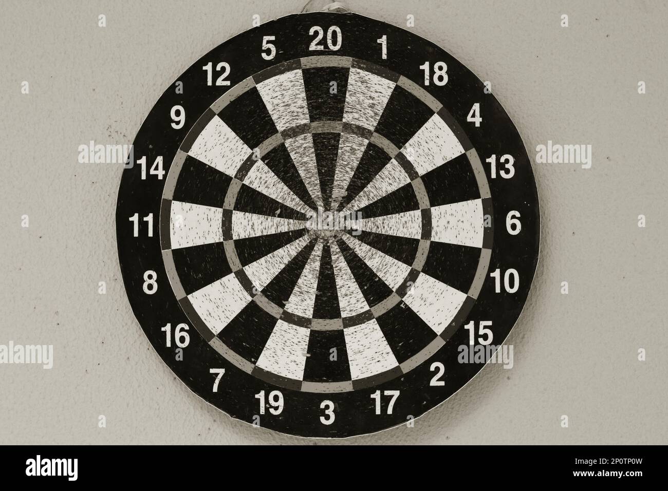 Old dartboard punctured by darts on light wall. Background of an old ...