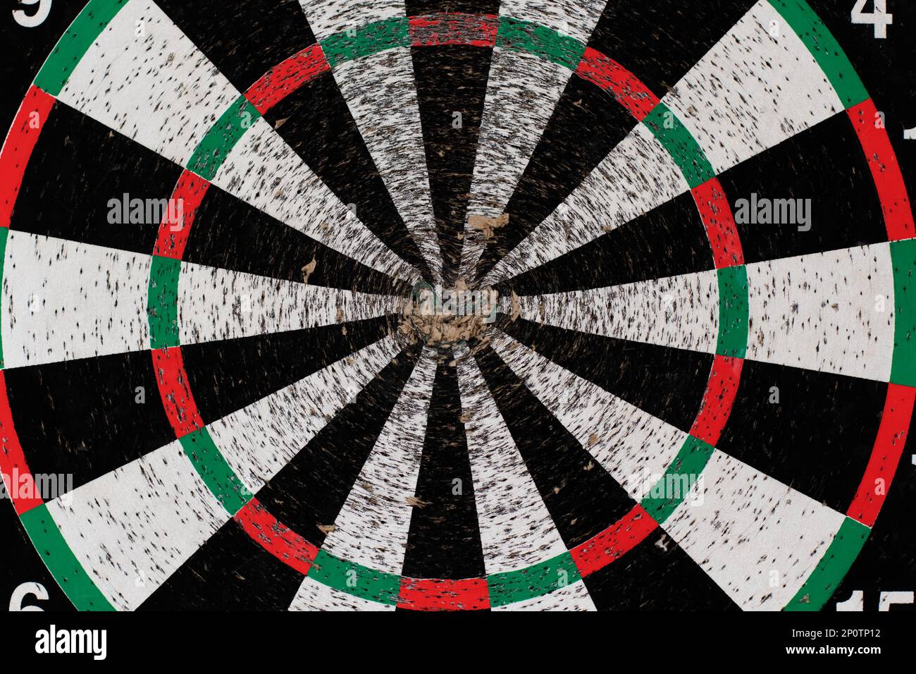 Old dartboard punctured by darts on light wall. Background of an old ...
