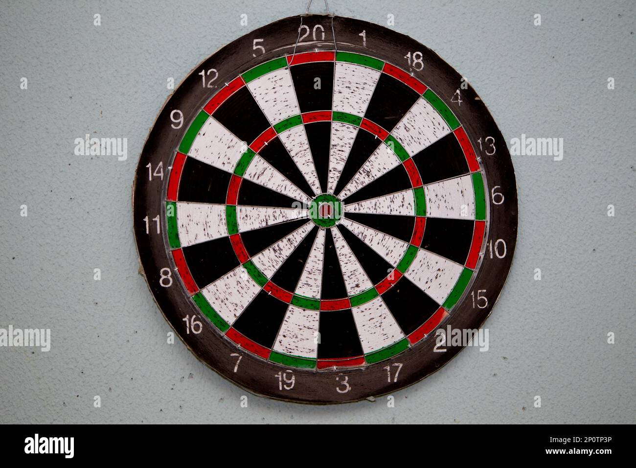 Old dartboard punctured by darts on light wall. Background of an old ...