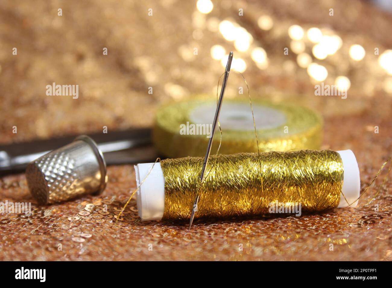 Gold Sequins on Fabric With Spool of Gold Thread and Thimble Stock ...