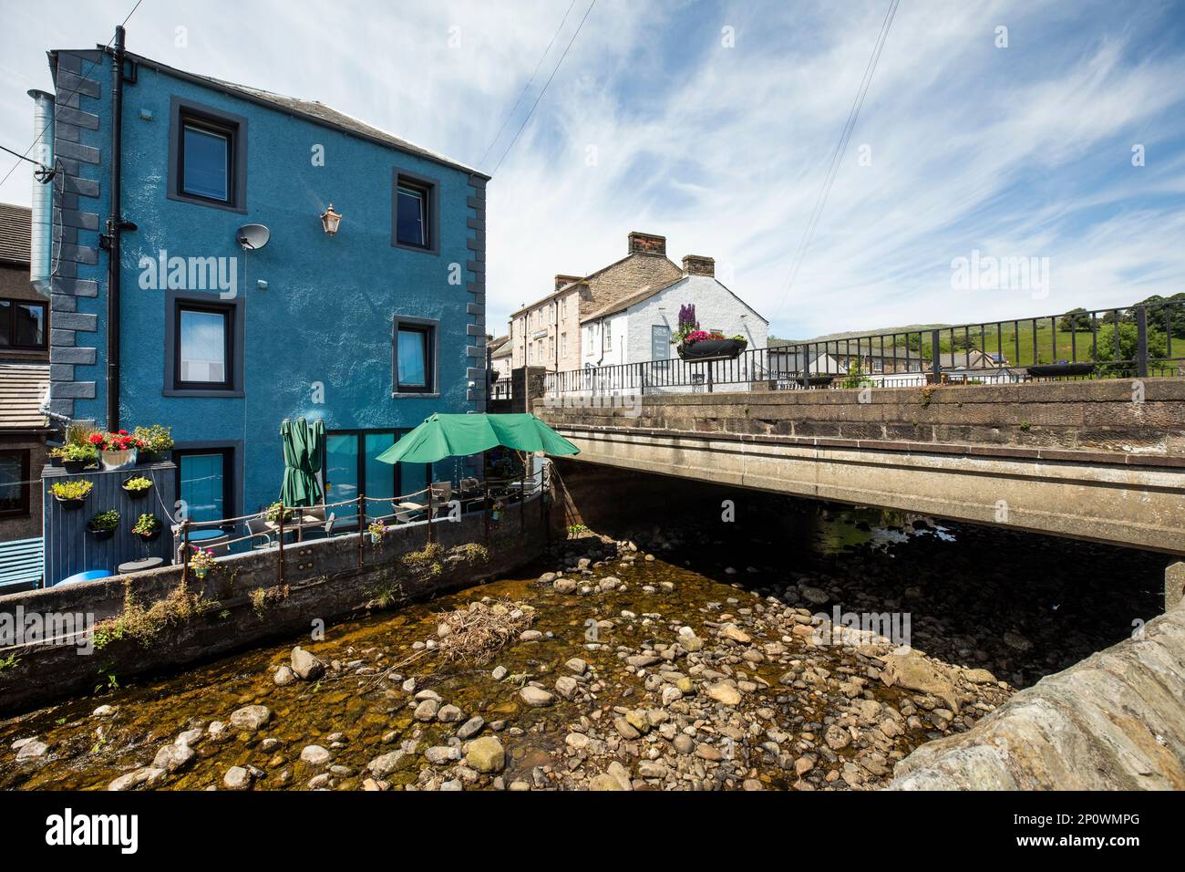 A pretty painted blue house stands by the side of the bridge over ...