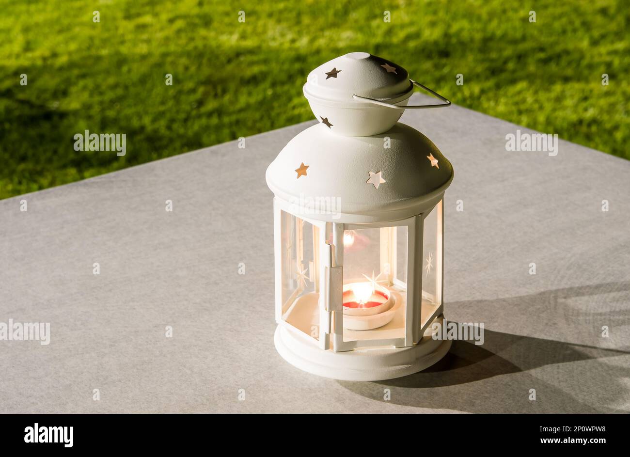 Lit lantern on a table in the garden at night Stock Photo - Alamy