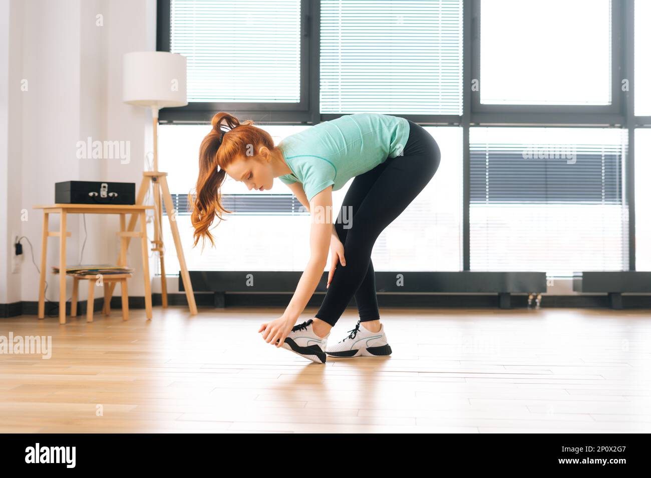 Flexible young woman practicing yoga, standing forward bend exercise ...