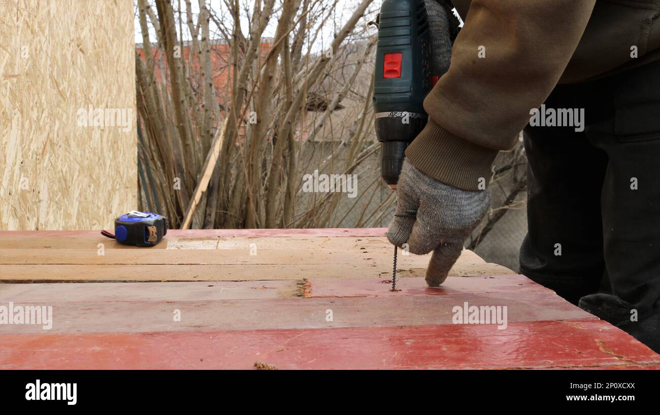 screwing a self-tapping screw into the surface of painted boards in the ...