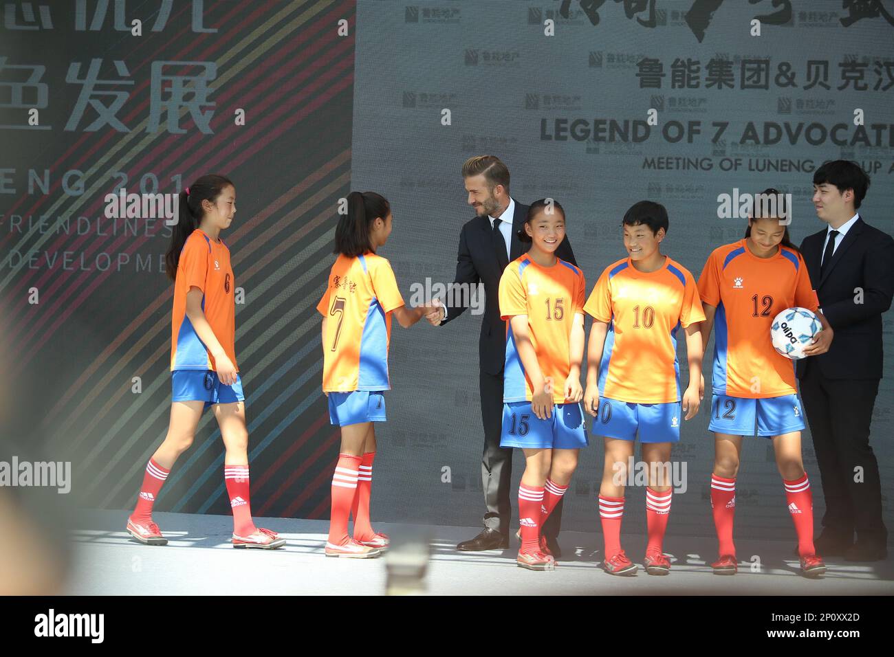 English soccer star David Beckham, center, shakes hands with a young ...