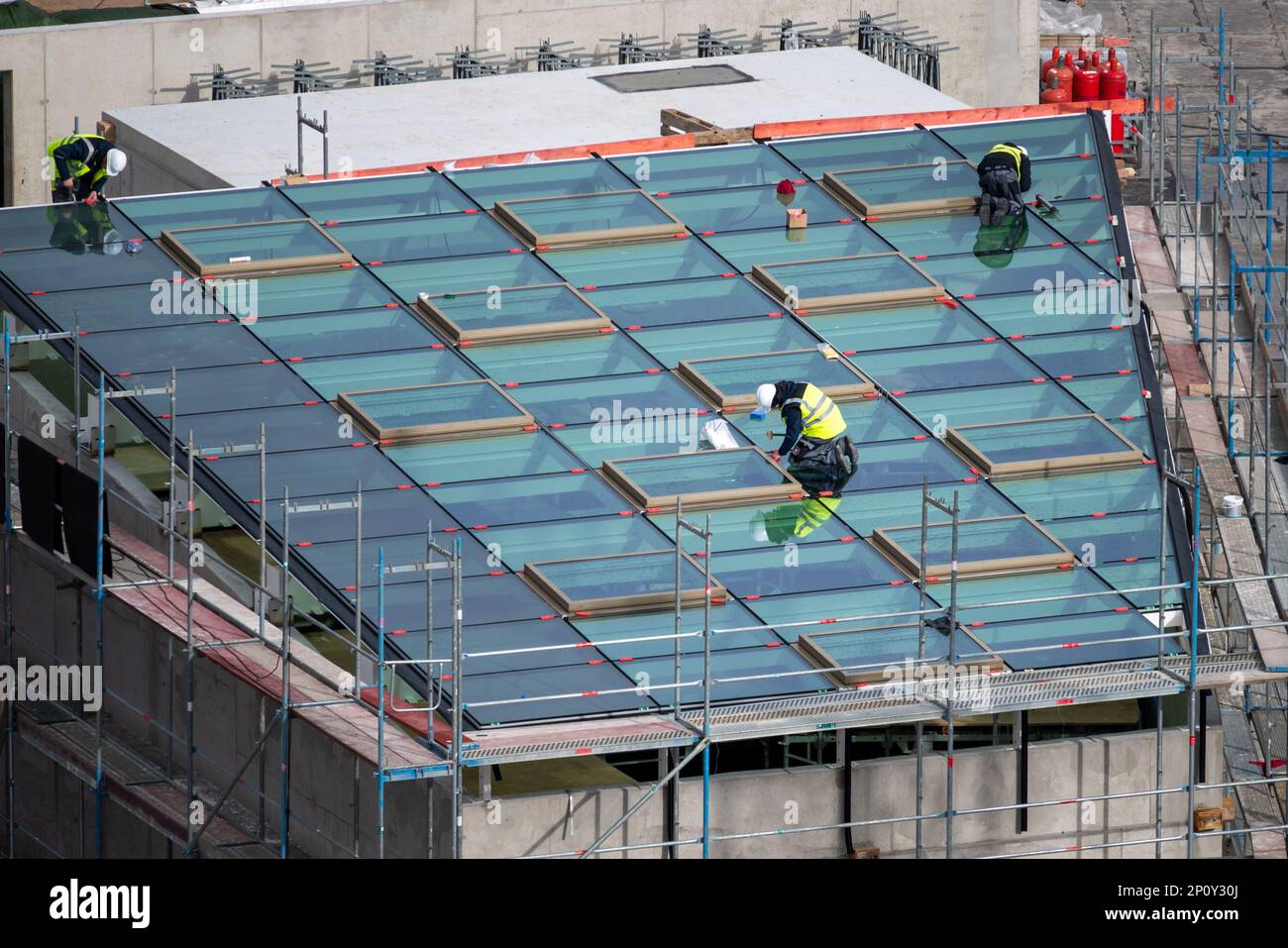 Roofer installing windows for a light well on the roof of a commercial ...
