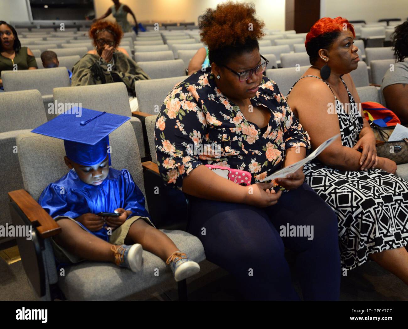 Jaylin Brooks, 2, (from left) is content sitting in his cap and gown ...