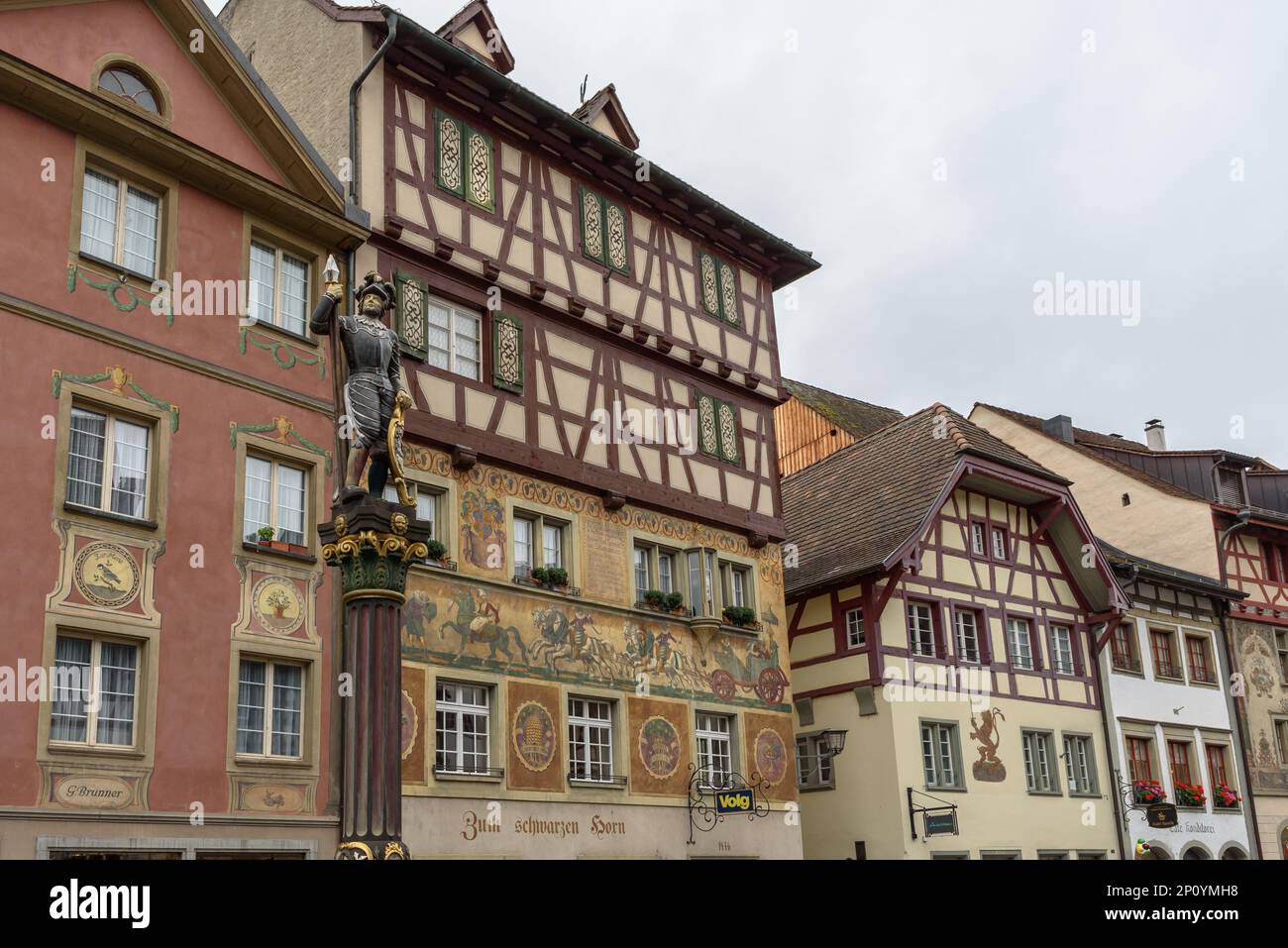 Sculpture on fountain and half-timbered houses with facade paintings in ...