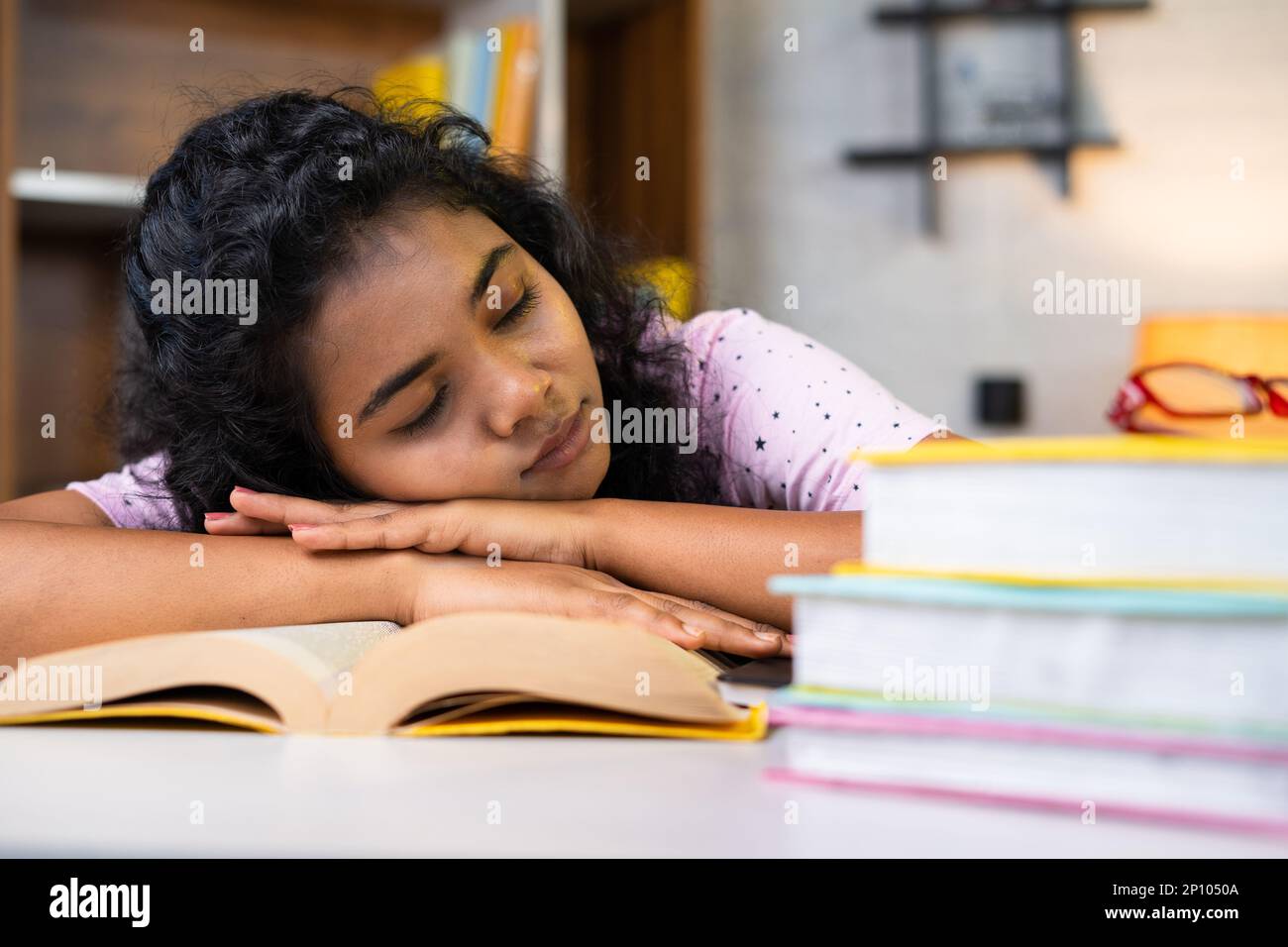 Tired young indian student sleeping on table during reading for ...