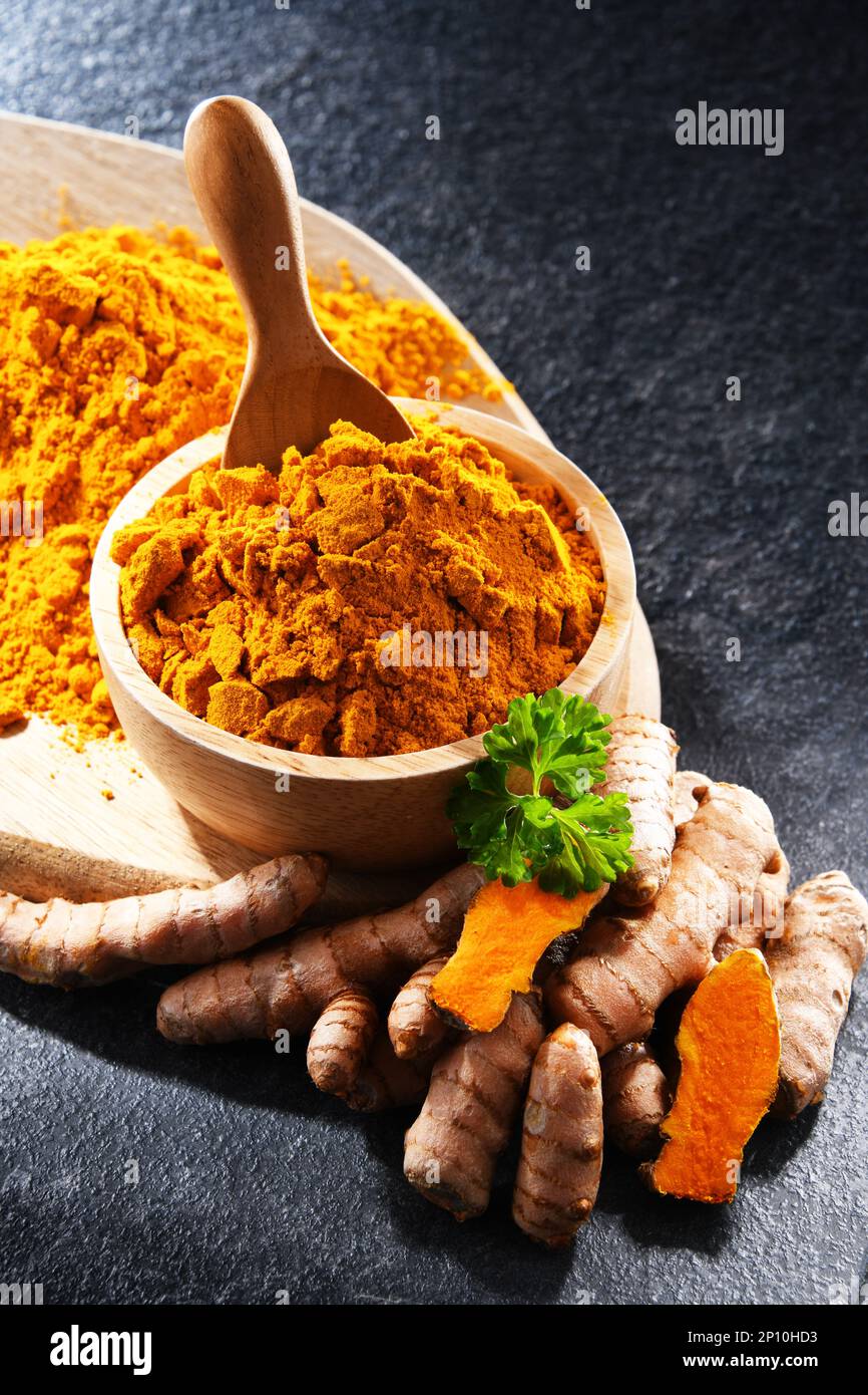 Composition with a bowl of ground turmeric and its fresh rhizome Stock ...