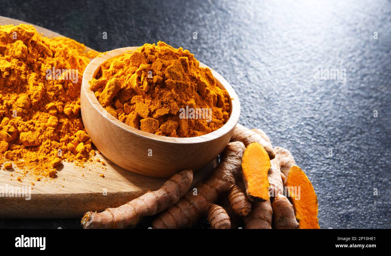 Composition with a bowl of ground turmeric and its fresh rhizome Stock ...