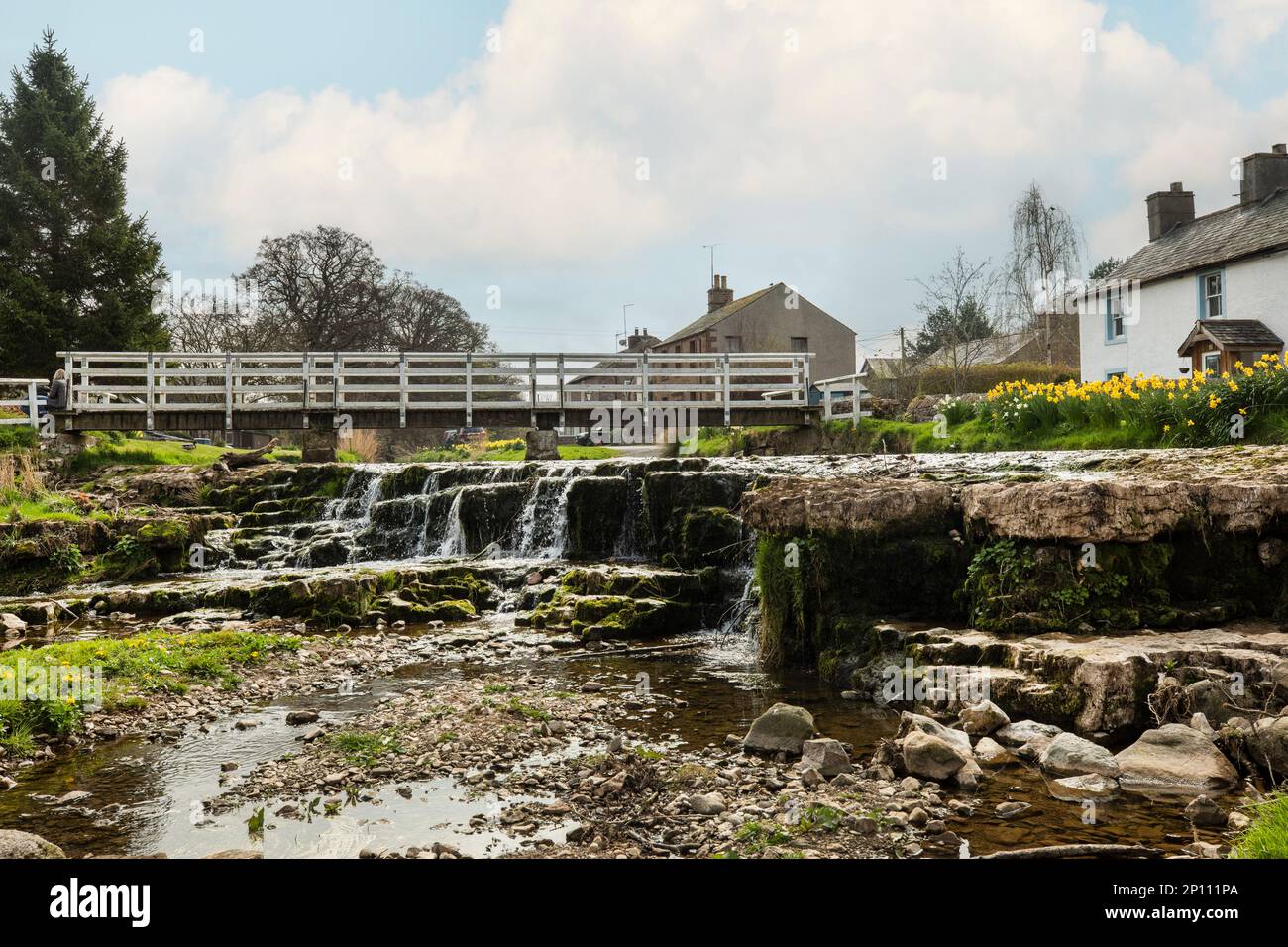 Wooden pedestrian white bridge crosses Morland beck above a small ...
