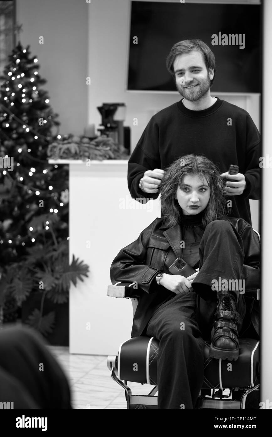 Beautiful young woman in modern hair salon. hairdresser checking ...