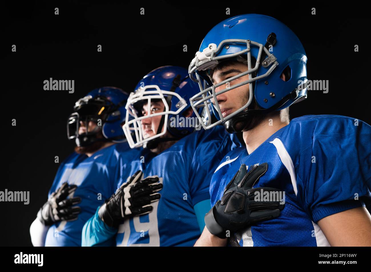 Portrait of three men in blue uniforms for American football with a ...