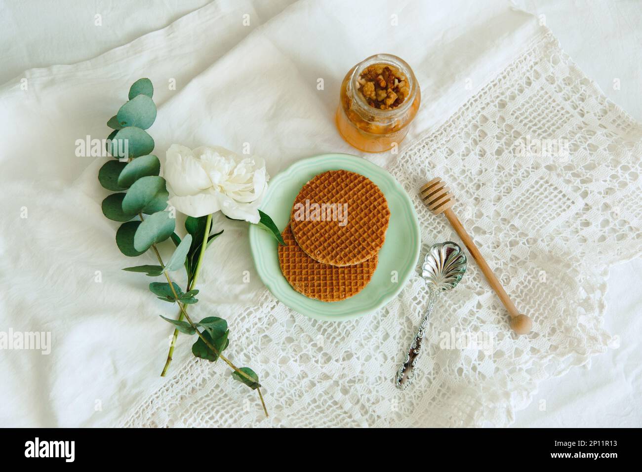 Two waffles on mint plate and honey with flower on the table. still ...