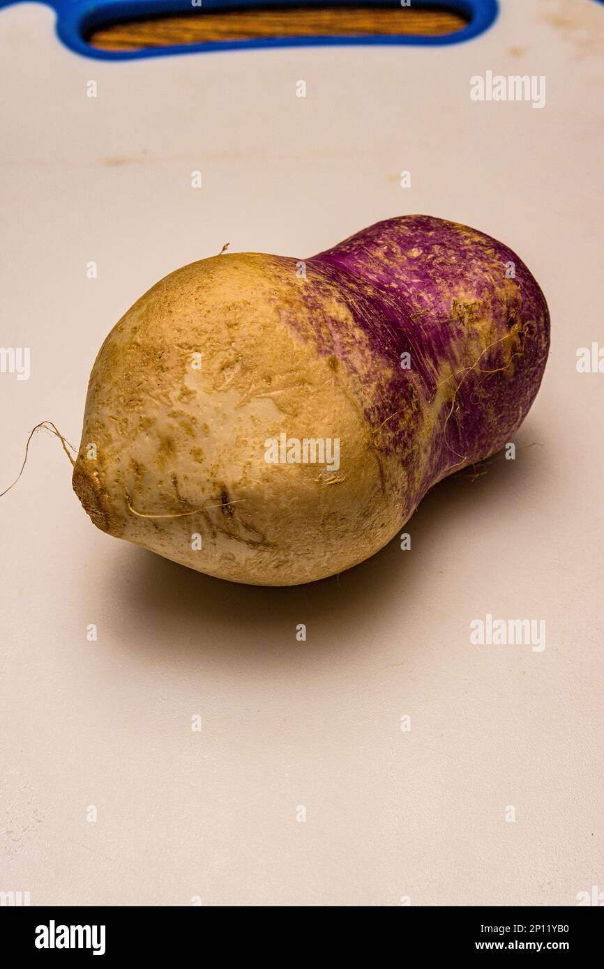 A common turnip with an odd shape on a kitchen cutting board Stock ...