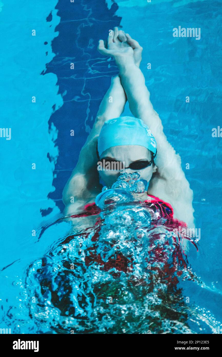 Top view of a young female swimmer training in the pool, swimming on ...