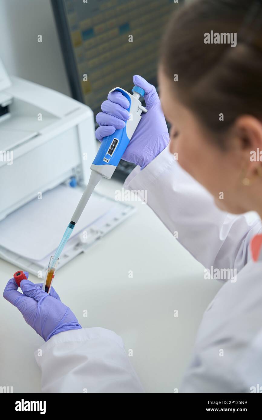 Woman collects biomaterial from a test tube with special dispenser ...