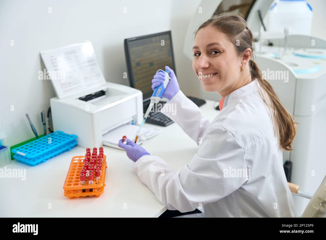 Smiling laboratory employee at her workplace works with blood samples ...