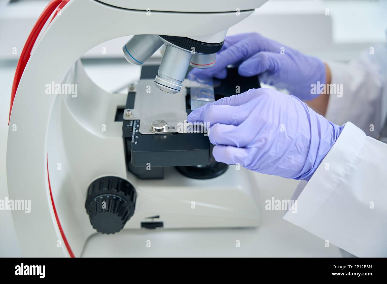 Laboratory employee places a biomaterial for dna test under microscope ...