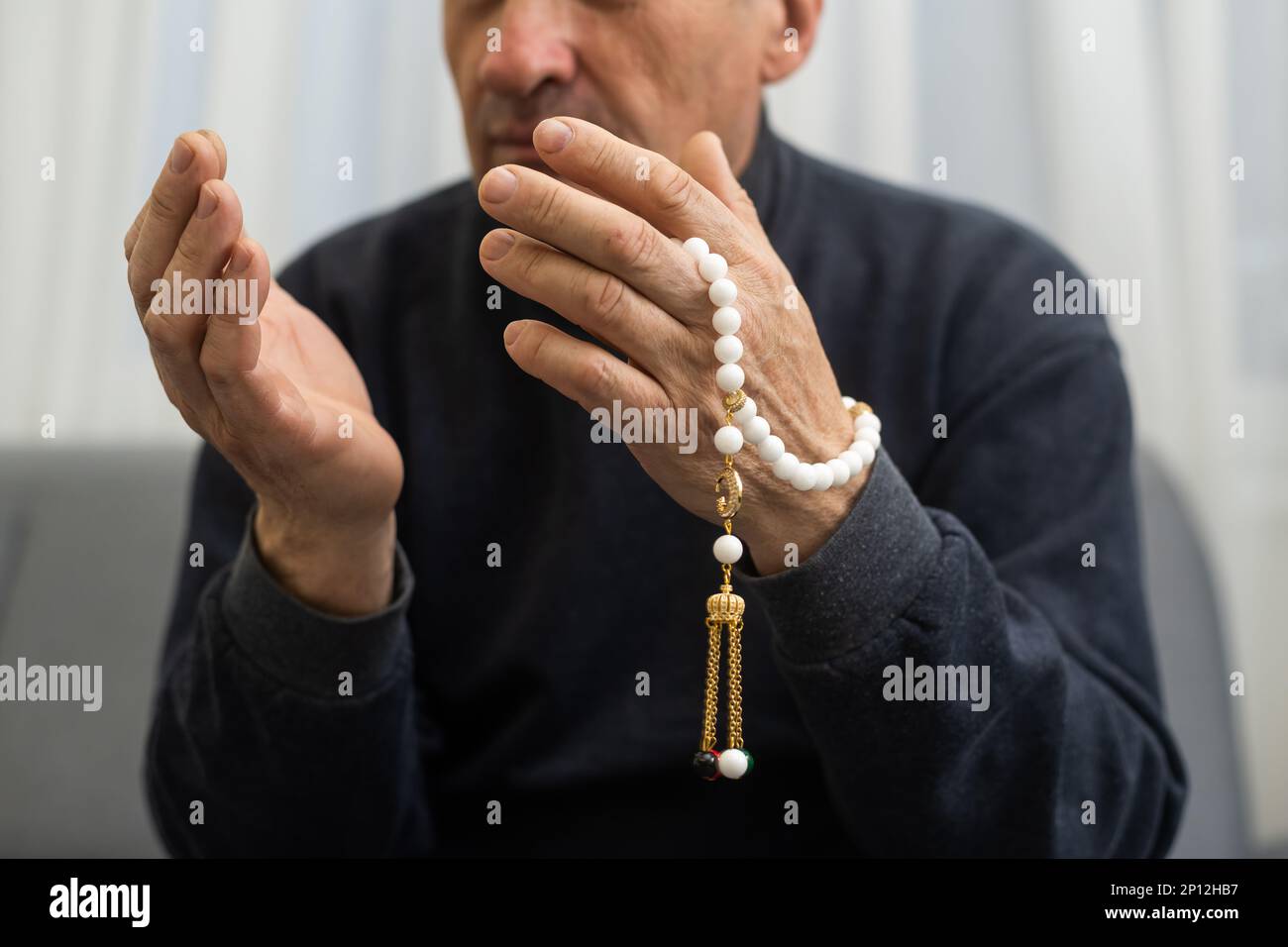 Praying hands of an old man holding rosary beads Stock Photo - Alamy