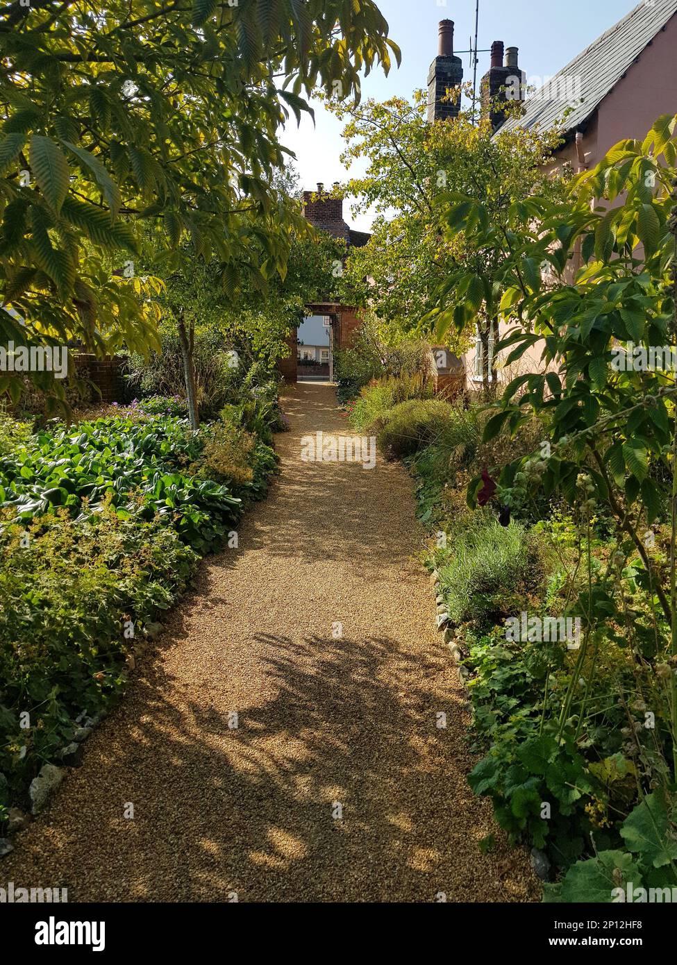 View of a garden path leading to an archway in a red brick wall Stock ...