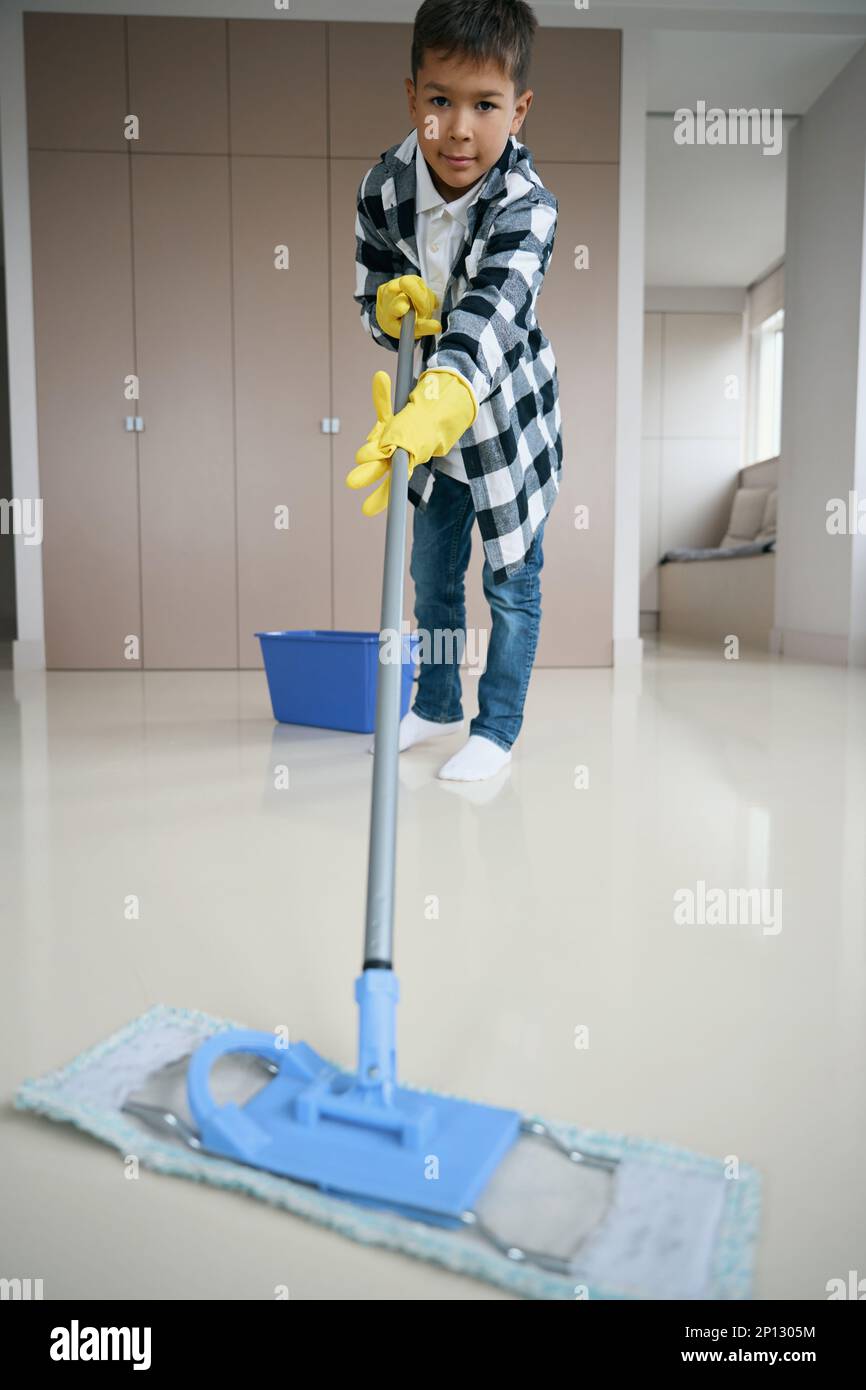 Cute child mopping floor in the living room with mop Stock Photo - Alamy