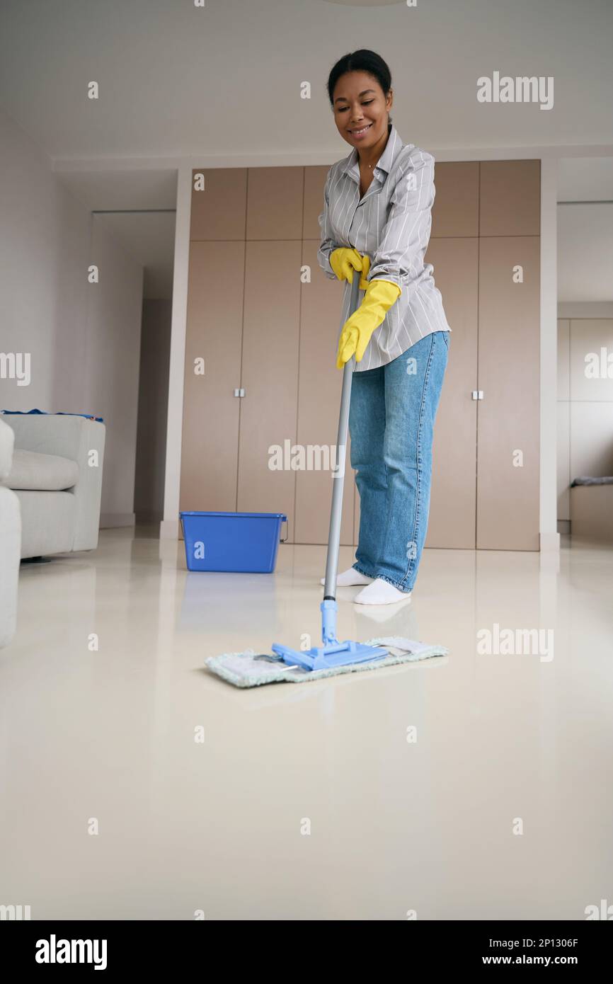 Female african american mopping floor in living room Stock Photo - Alamy