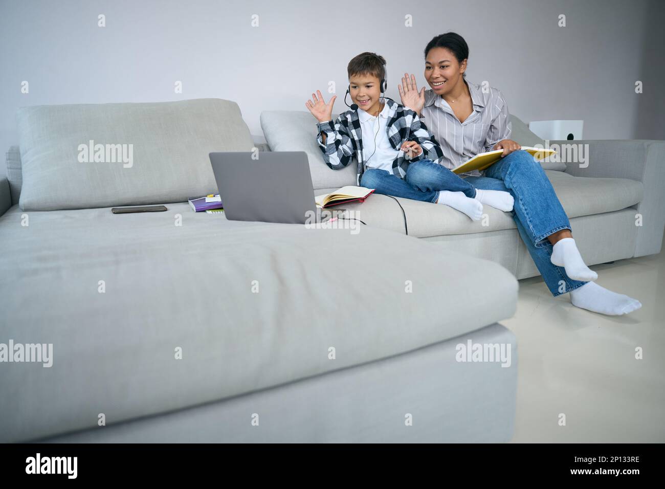 Online learning home, boy and his mom are sitting on couch Stock Photo - Alamy