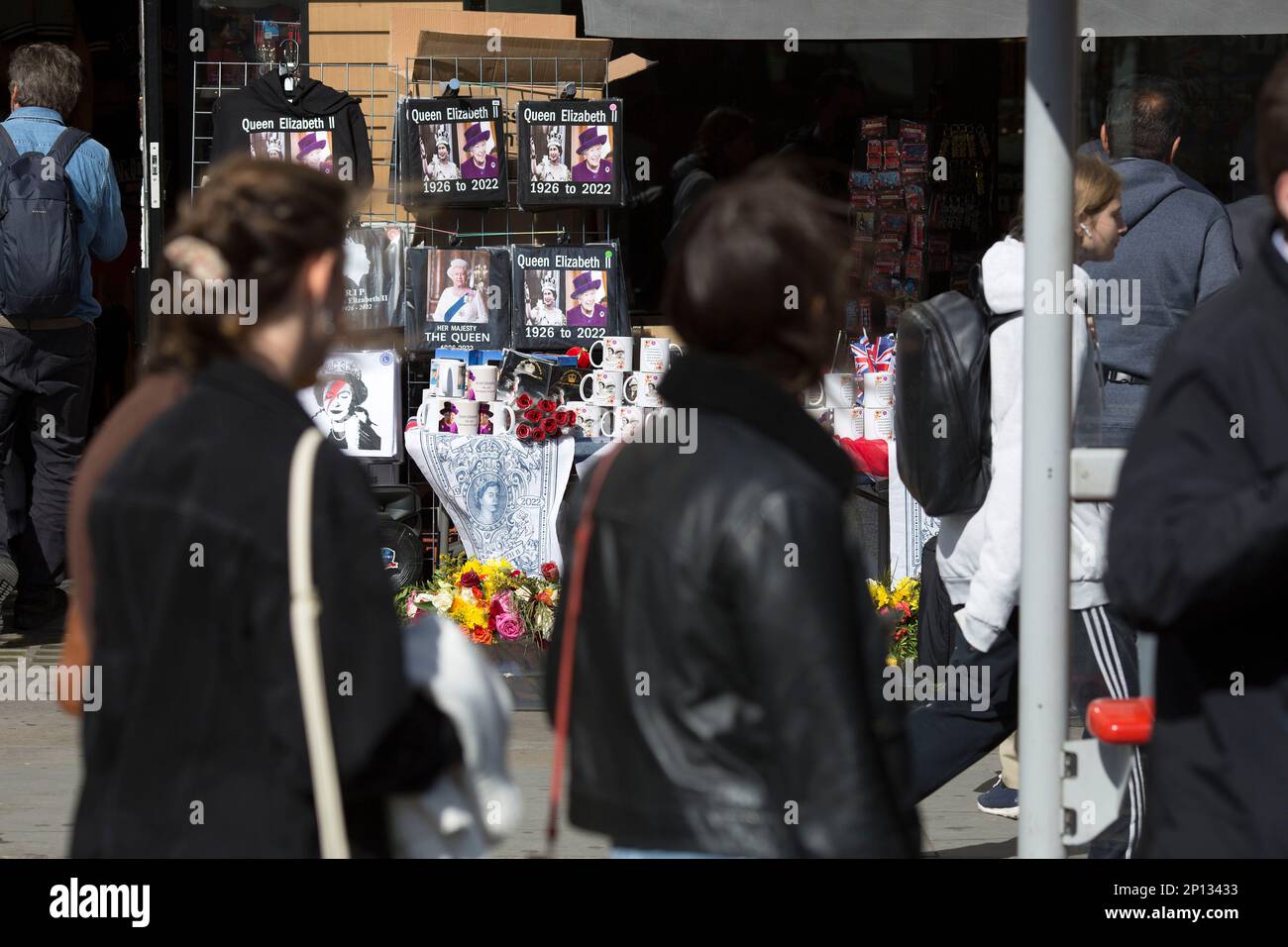 Images of the late Queen Elizabeth II are seen as people queue and wait ...