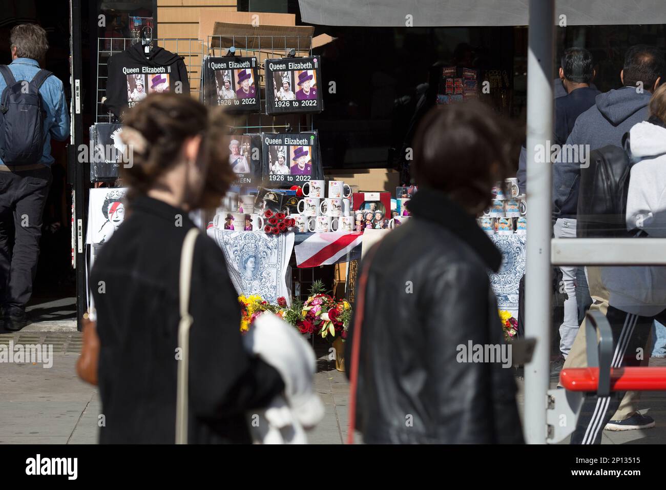 Images of the late Queen Elizabeth II are seen as people queue and wait ...