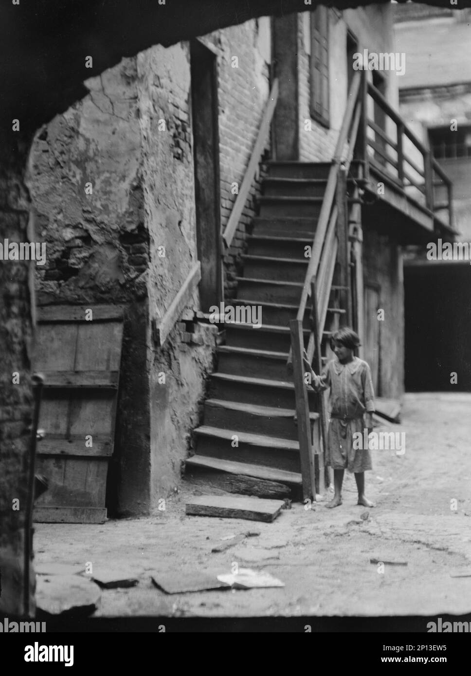 Child standing next to a stairway in a courtyard, New Orleans, between ...