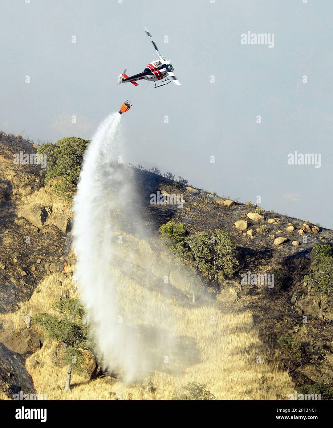 Cal Fire helicopter 106 makes a water drop along a ridge above the ...