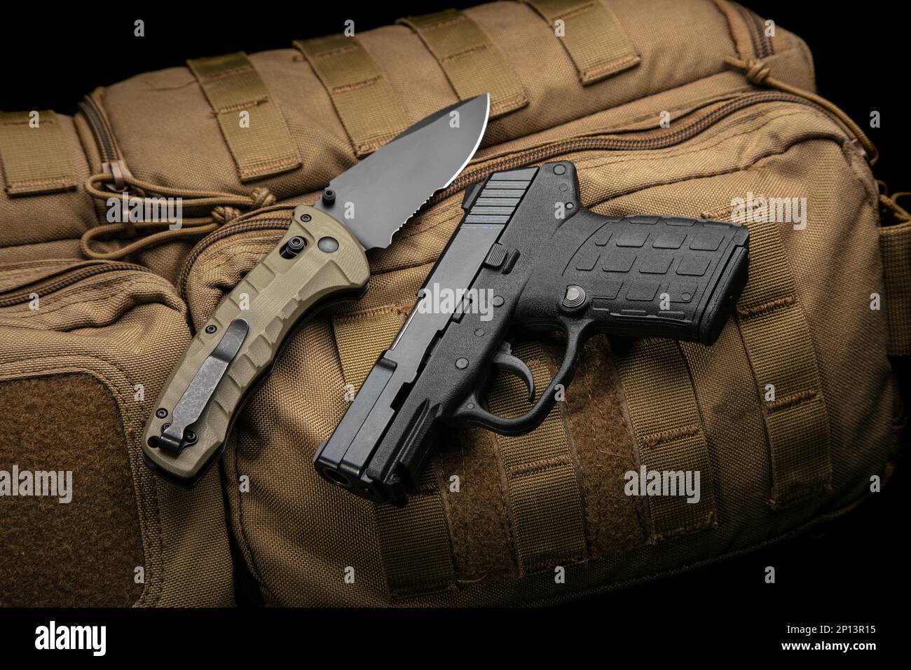 A small modern pistol and penknife on a brown military backpack. Self ...
