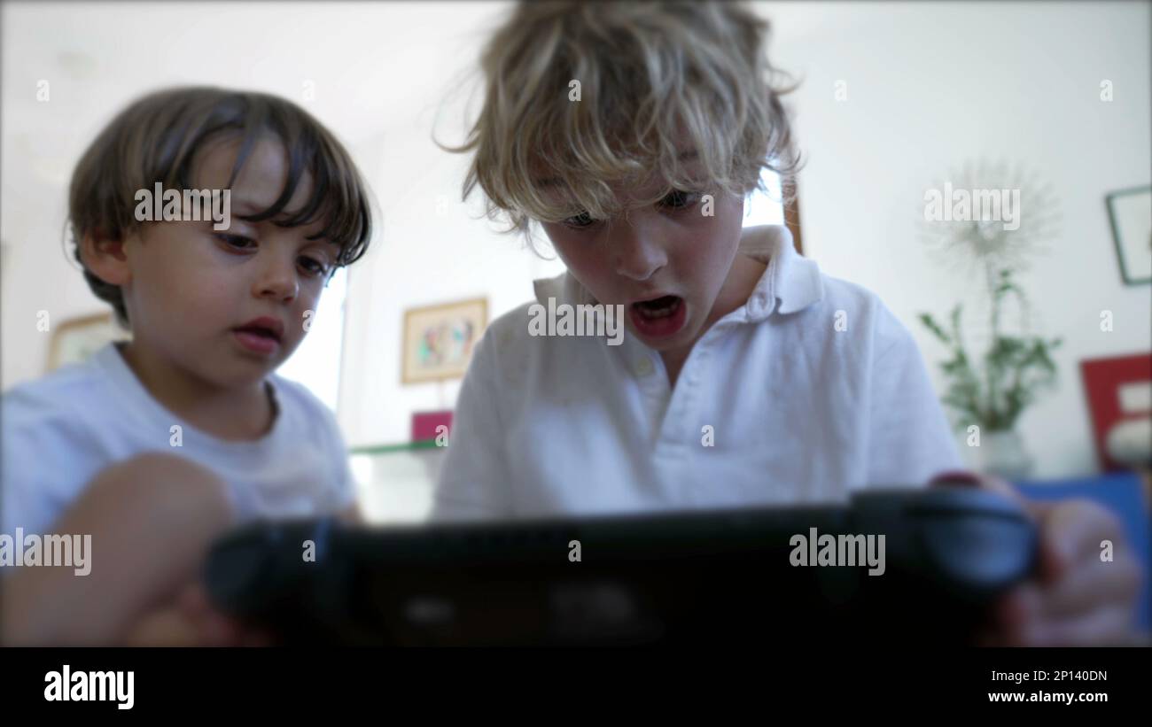Children in front of video game console screen. Baby brother watching ...