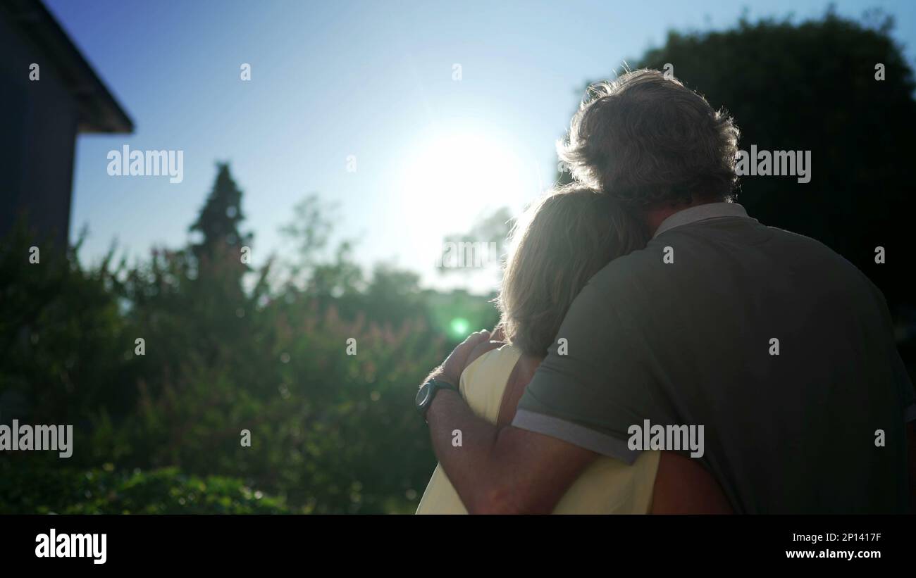 A senior couple standing with arms around each other stands outdoors ...