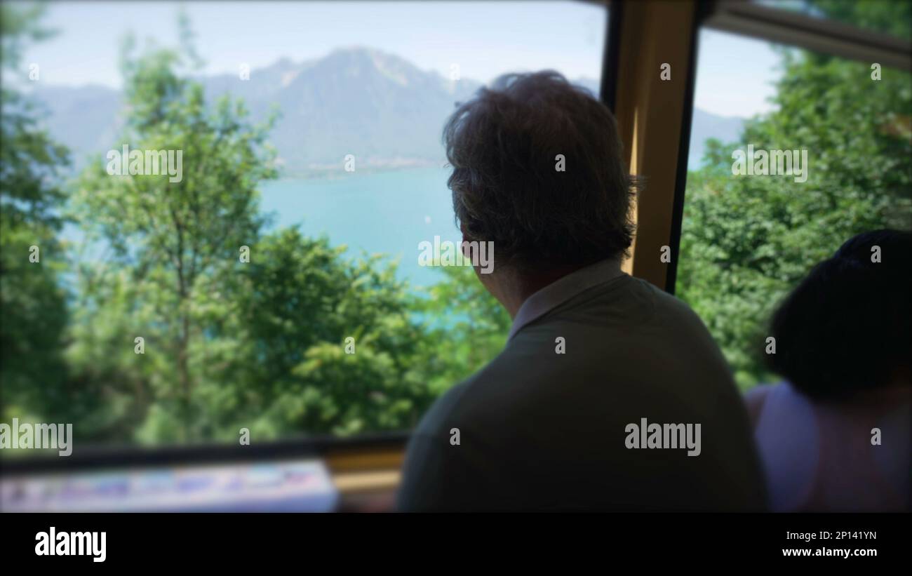 Back of senior man inside train looking out window. Passenger person ...