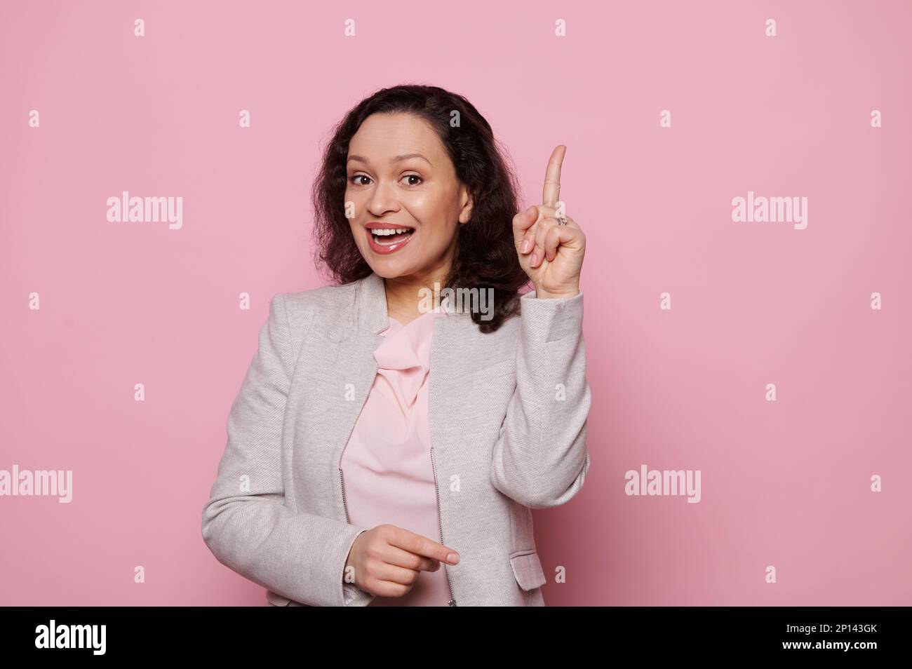 Charming woman pointing her index finger up, expressing idea and ...