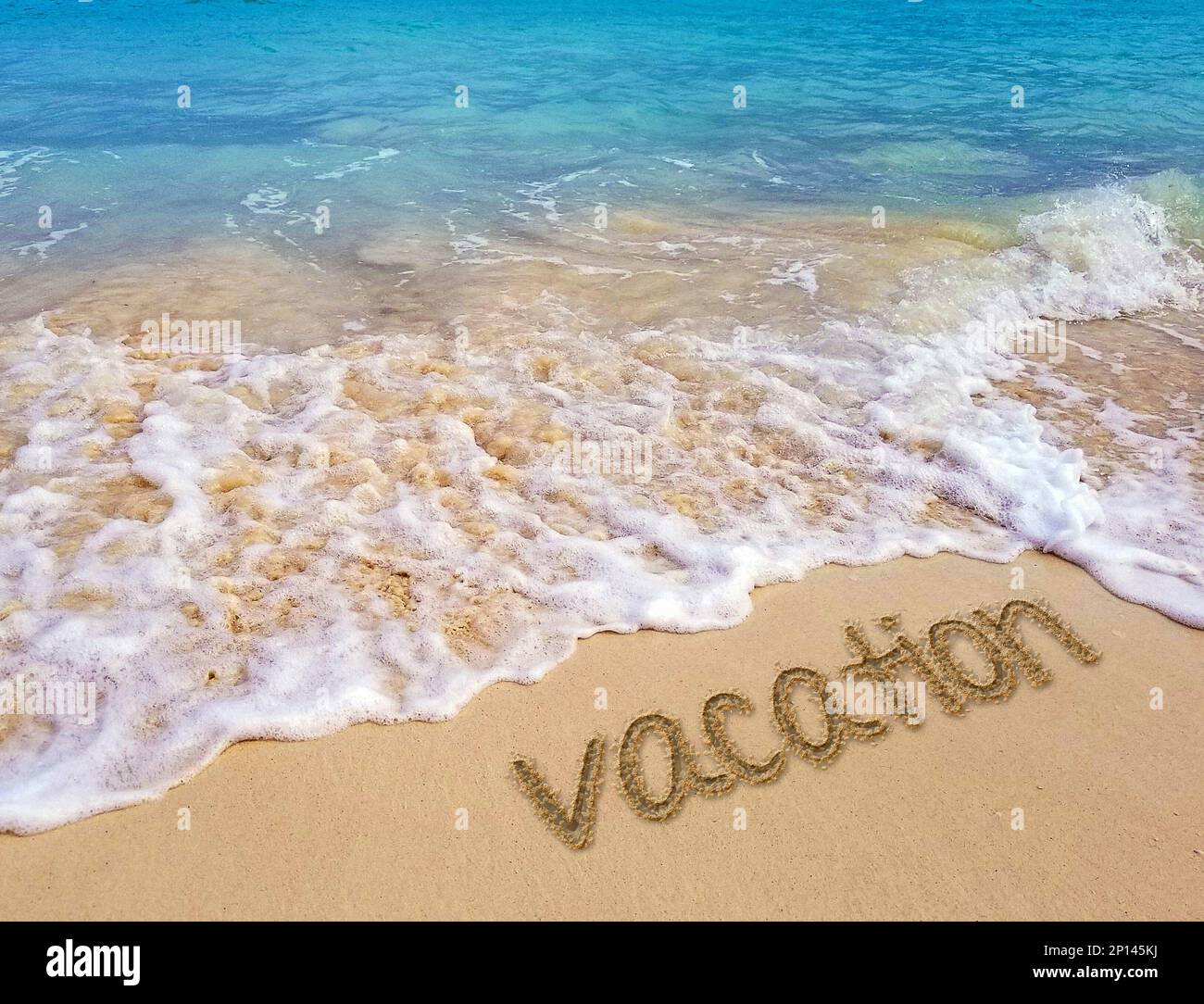 Vacation text in beach sand with frothy ocean water Stock Photo - Alamy