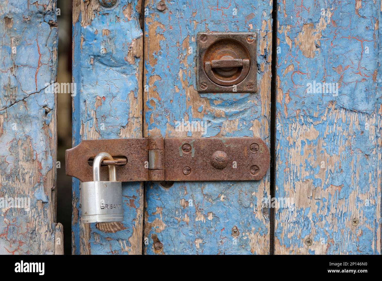 Lock and padlock on a distressed blue painted wooden personnel door ...
