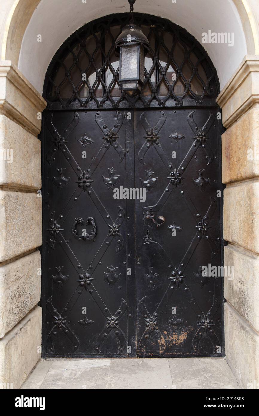 Old massive swinging metal forged doors with ornaments in a historic ...