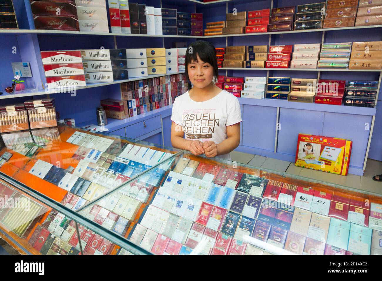 Young shop assistant woman girl and display of cigarettes and other ...
