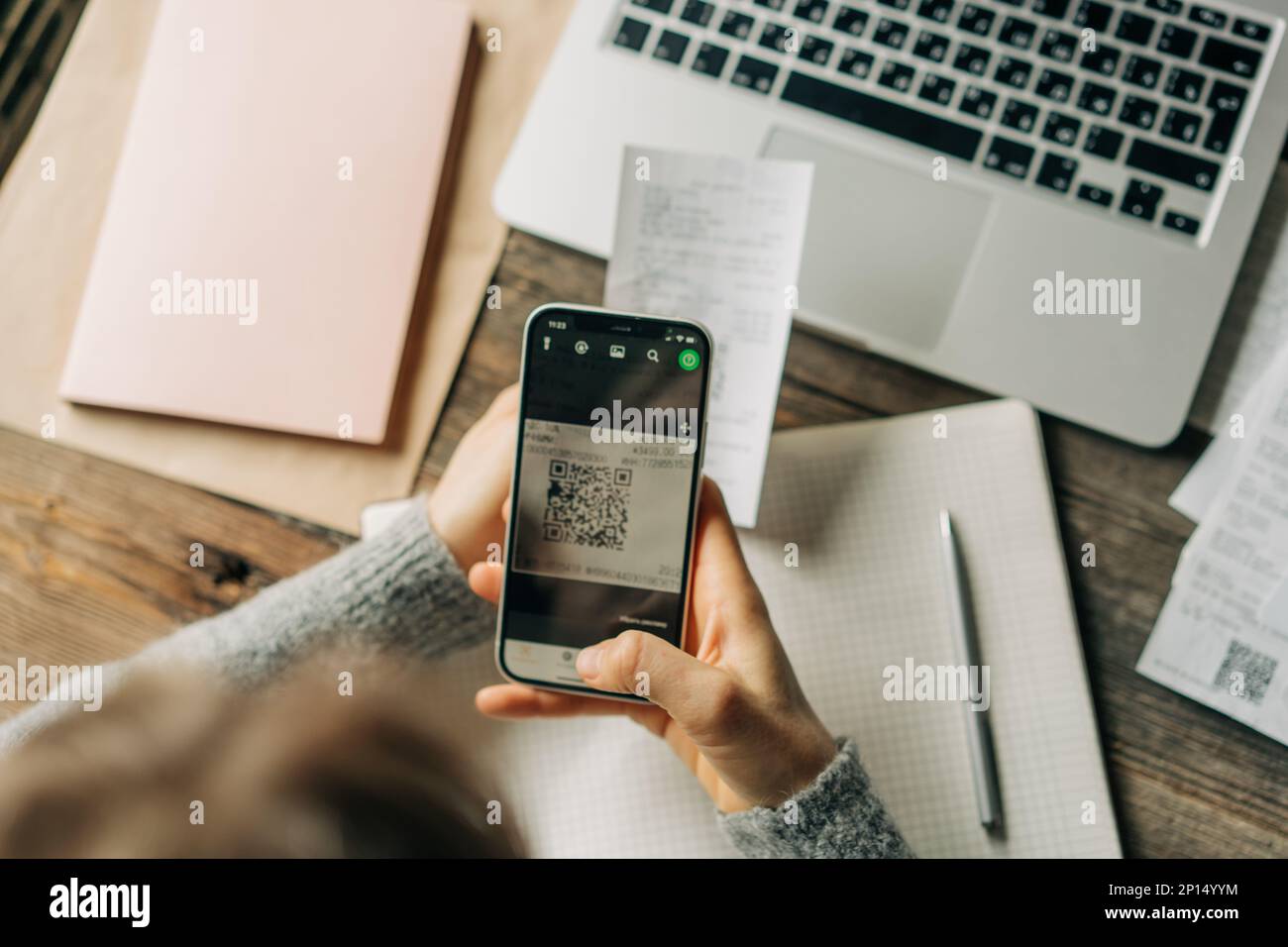 An unrecognizable woman works with bills using a qr code reader app on ...