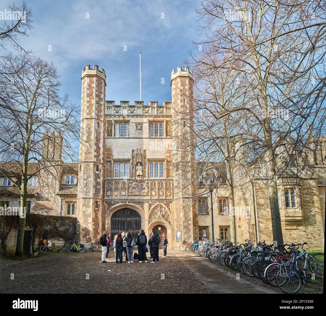 A group of tourists outside the towered entrance to Trinity college ...