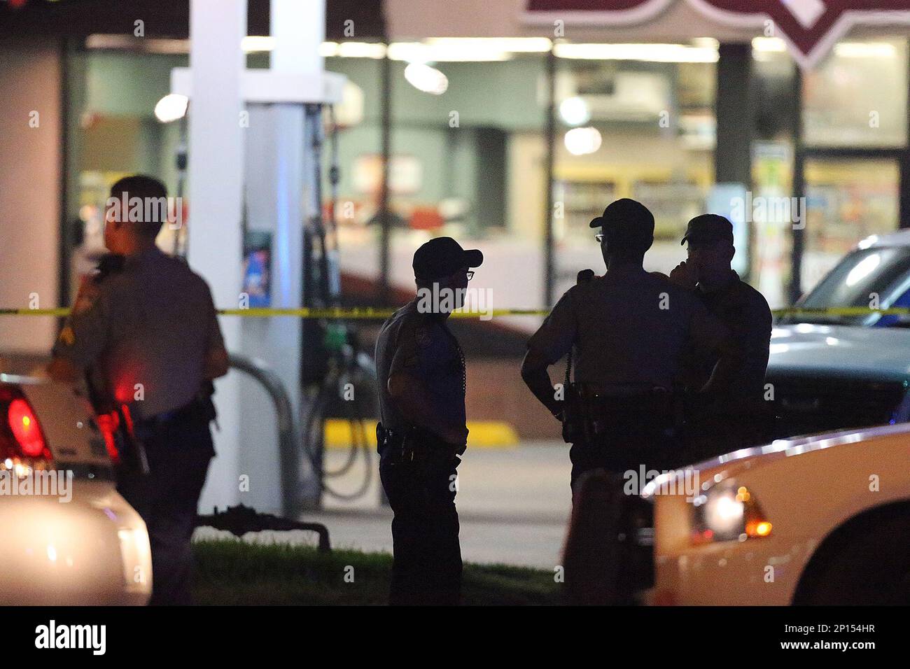 Law enforcement officials work the crime scene at the B-Quick gas ...