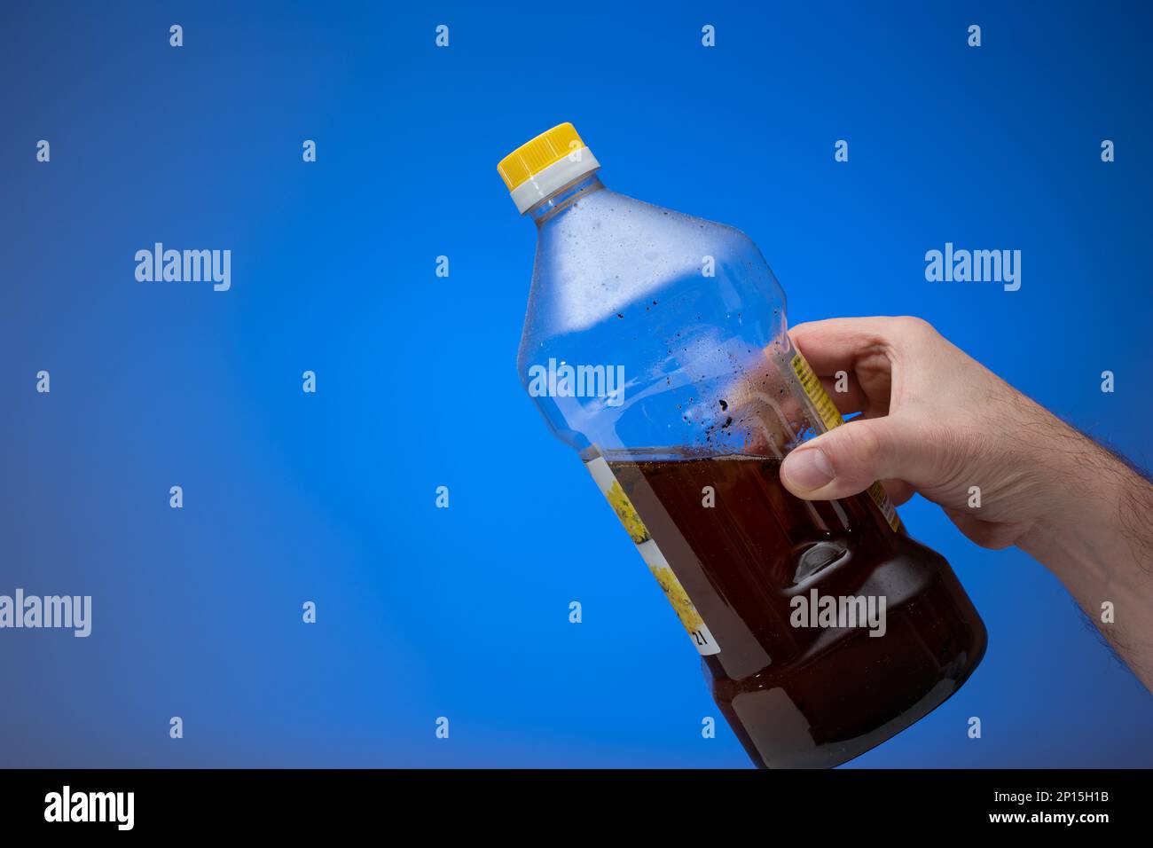 Spent cooking oil recycling in a clear plastic bottle. Held in hand by ...